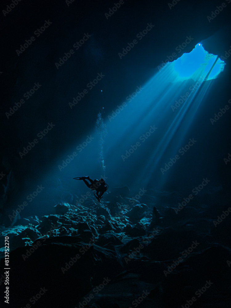 Diver caught in a beam of light in the underwater cavern at Buford Sink ...