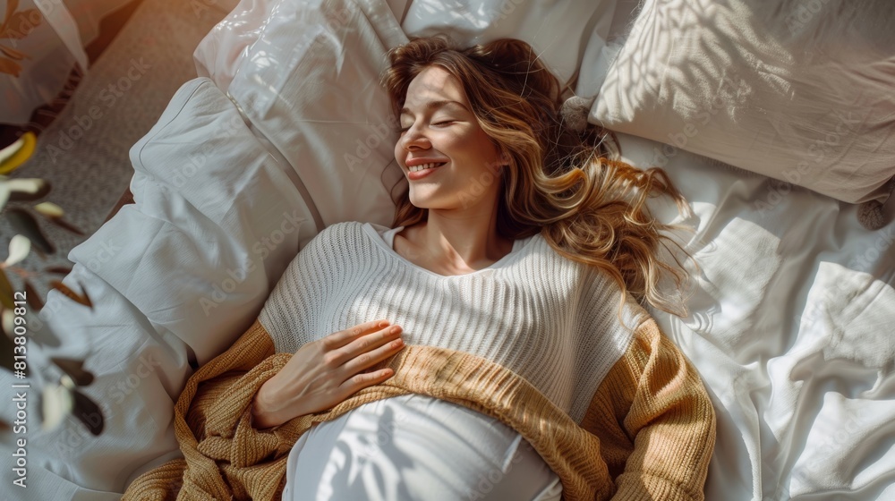 This beautiful young maternity model is lying in bed in the morning ...