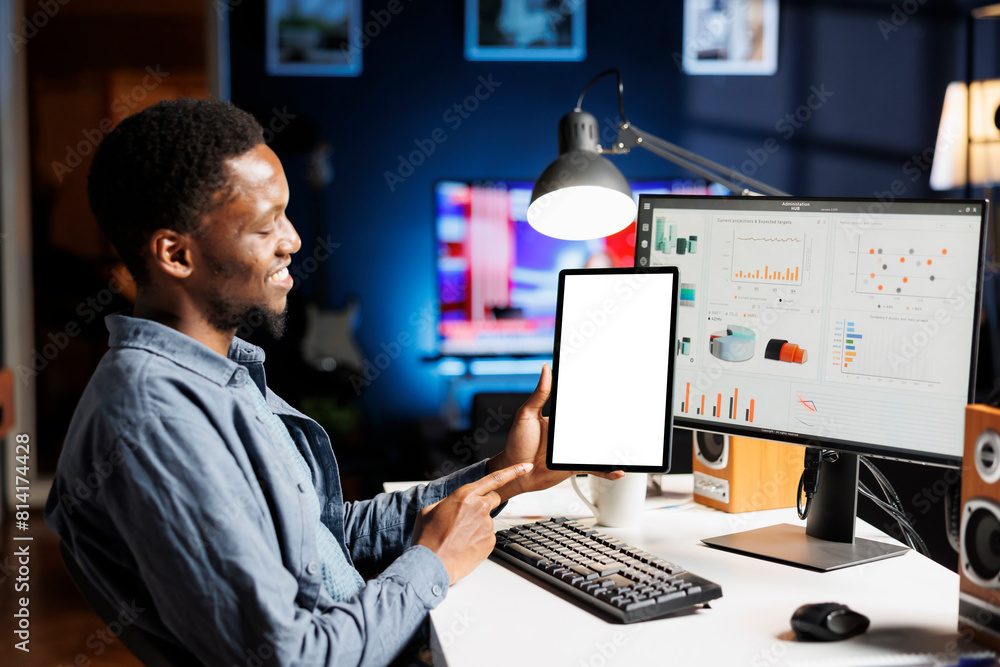 Young person working on tablet with blank display, sitting at his workstation before evaluating ...