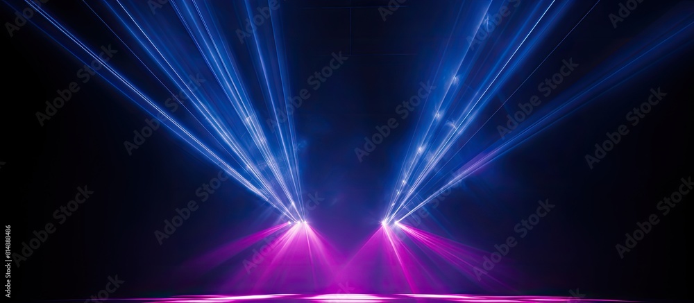 Stage spotlights cast pink beams of light against a dark blue backdrop ...
