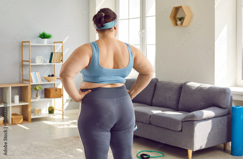 Overweight woman in sportswear during workout at home. Backside shot of ...