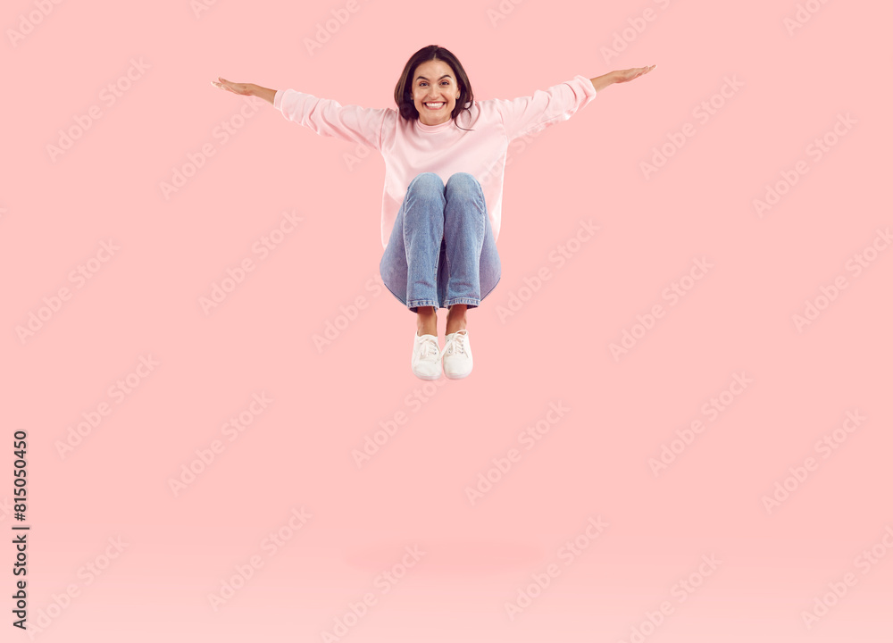 Happy young woman with outstretched arms jumping on trampoline ...