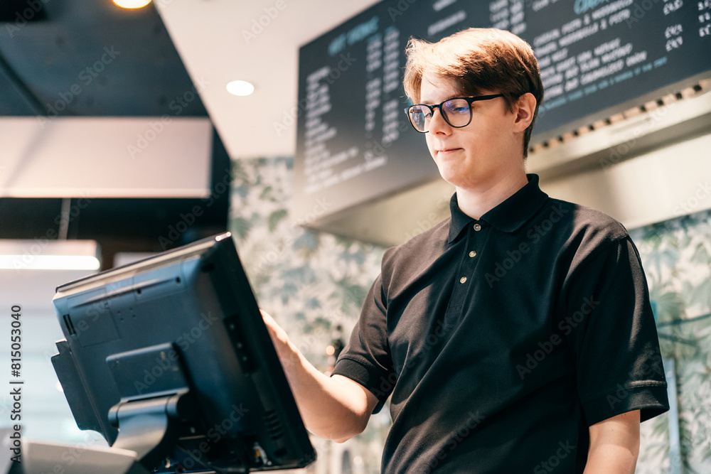 Young waiter serving customer at cash point in cafe. Man working with ...