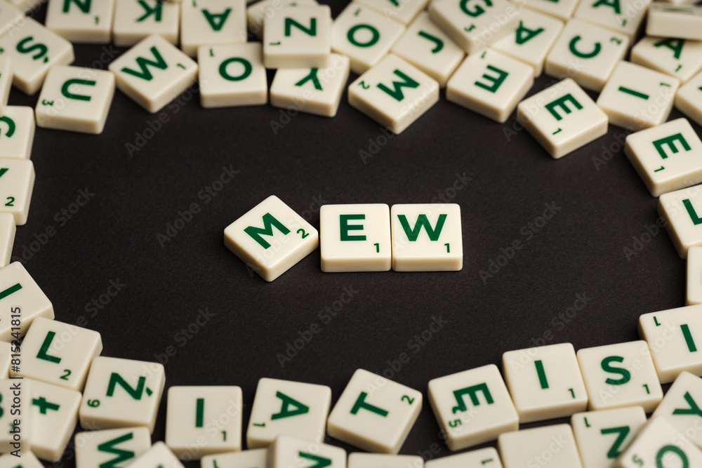 The inscription "MEW" made of game letters on a black background ...