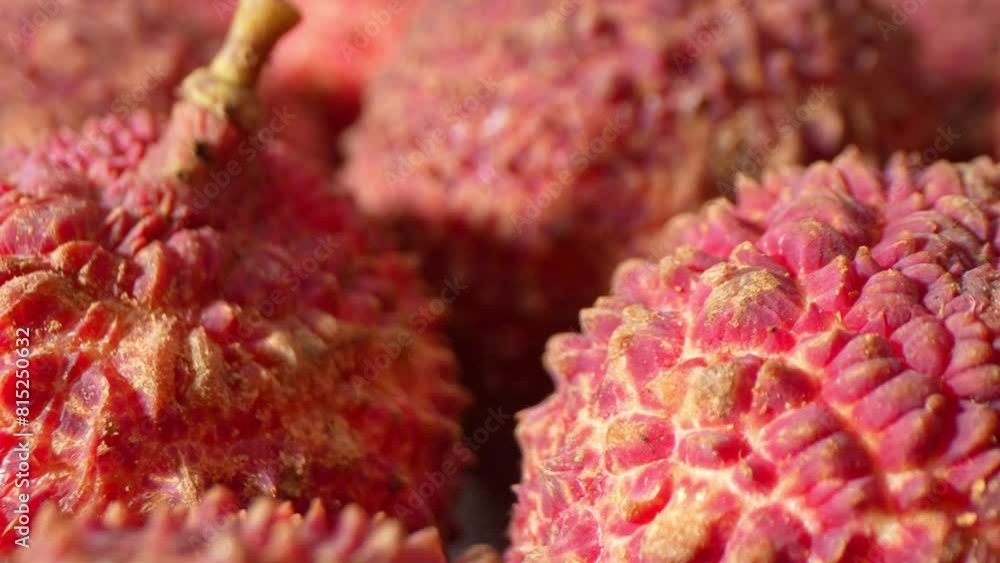 In a captivating close-up, the rough, reddish-pink skin of lychee ...