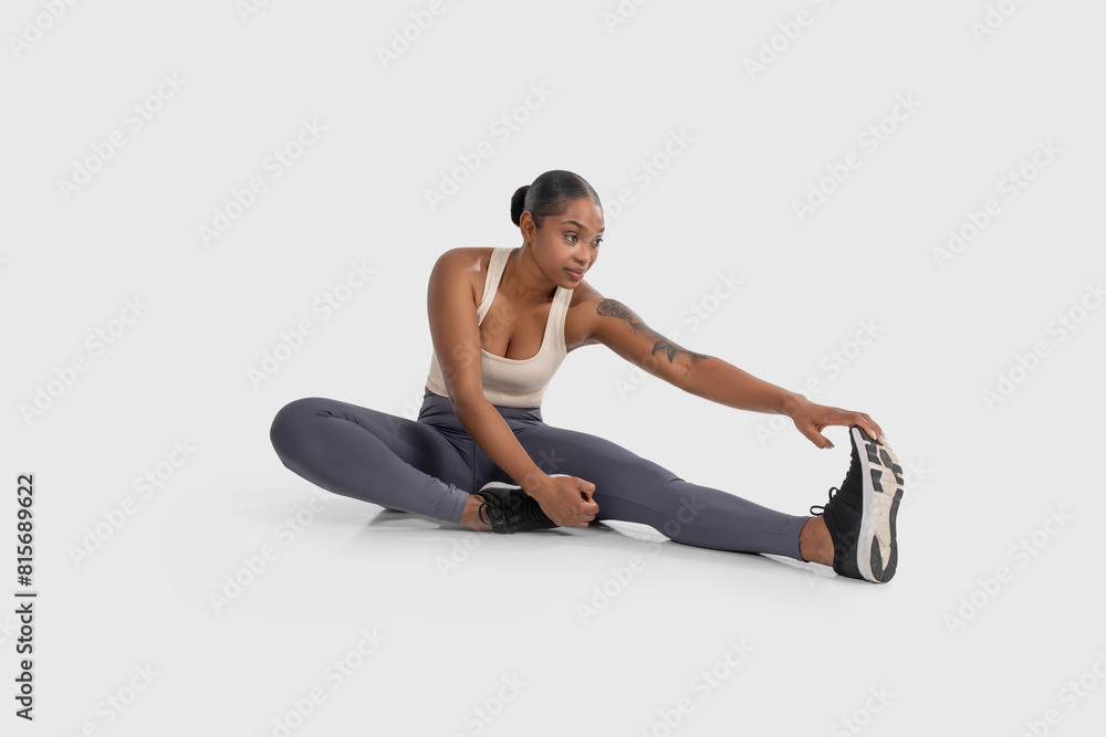 African American woman is engaged in a stretching exercise on the floor ...