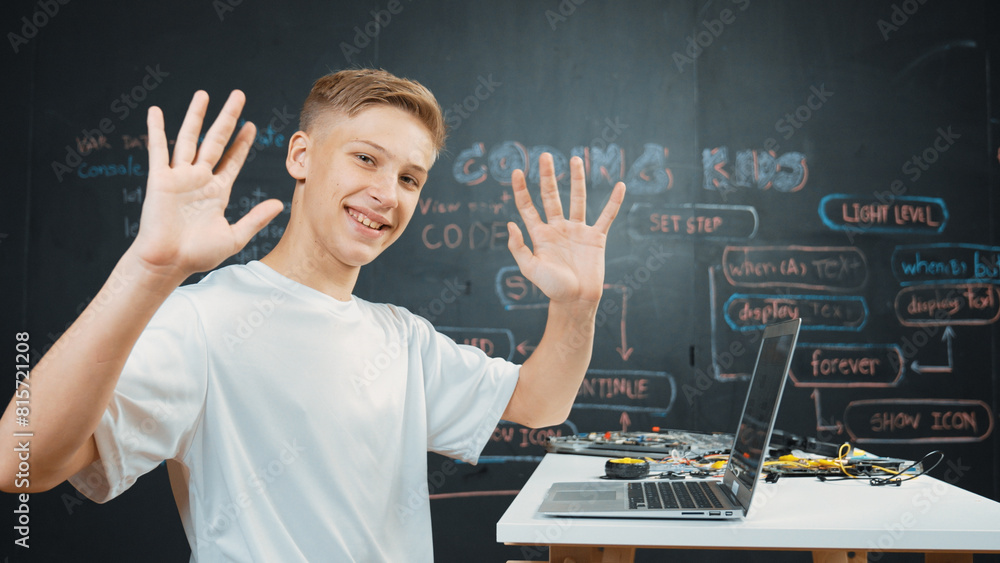 Side view of young boy programing code while looking at camera and ...