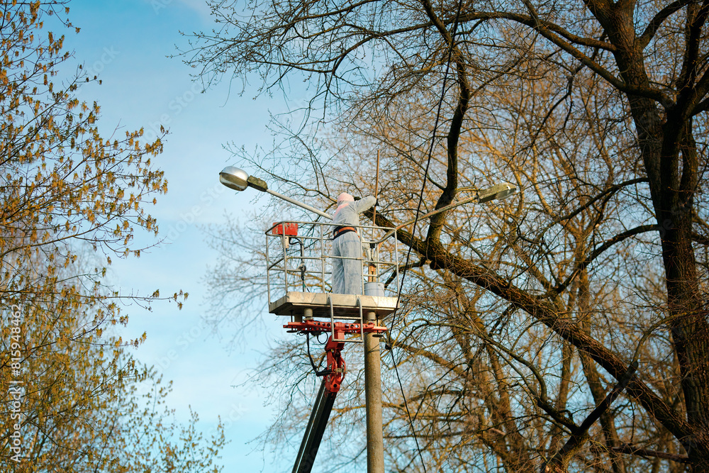 Painter in lift bucket paint street lighting pole at height. Man in ...