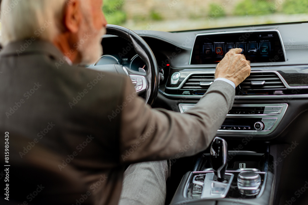 Senior gentleman adjusting the touchscreen panel in a modern car ...