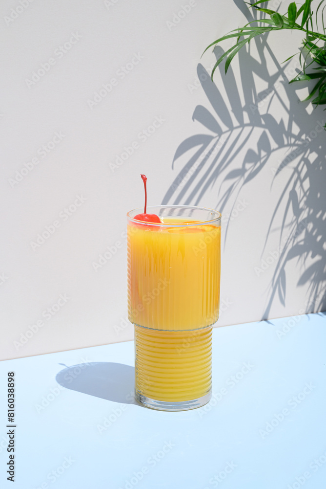 Orange juice drink decorating with cherry fruit and palm leaves on a ...