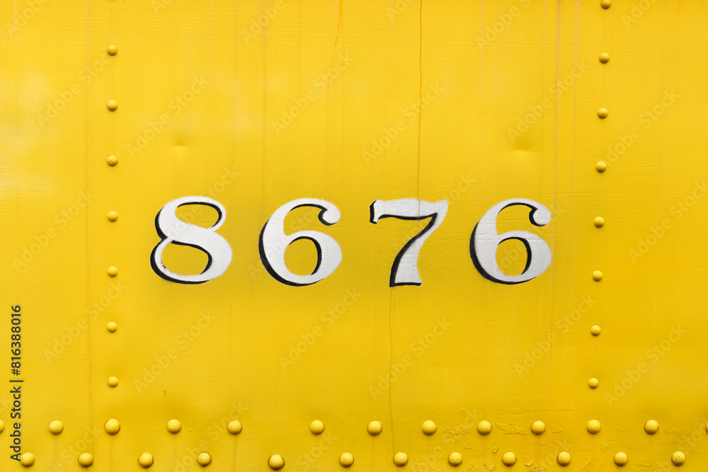 8676, stencil painted numbers on a vintage, antique train car. Yellow ...