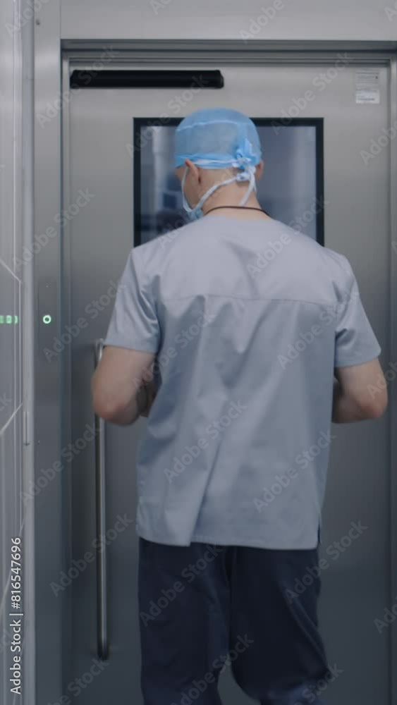 Back view of surgeon coming into surgery room after cleaning hands ...