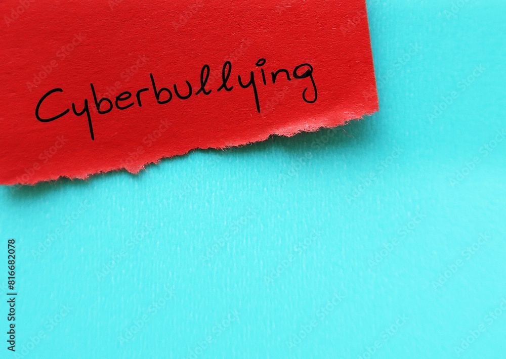 Red paper on blue copy space background with text CYBERBULLYING ...