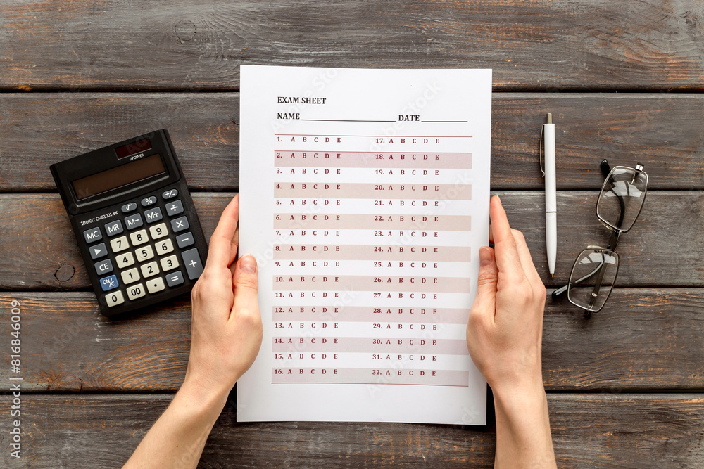 Female hand with answer exam sheet form on a table, top view. Education ...