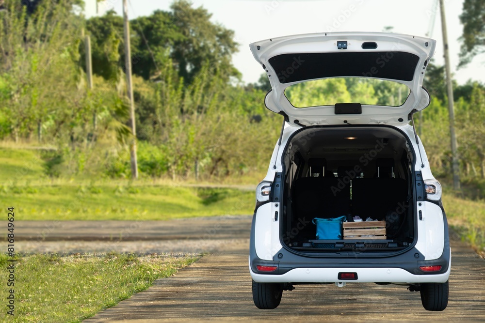 The rear view of a white car with an open trunk full of luggage on a ...