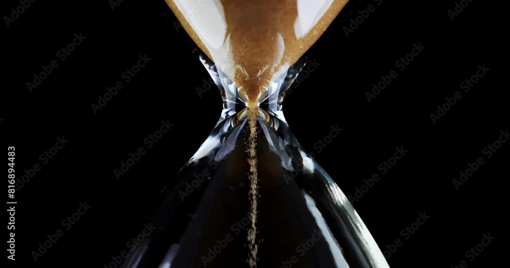 Hourglass. Sands move through hour glass. Sandglass close-up on a black ...