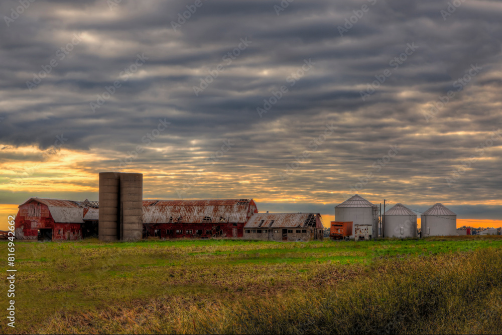 Barns and Silos. A dramatic sky with dark clouds hovers above a rustic ...