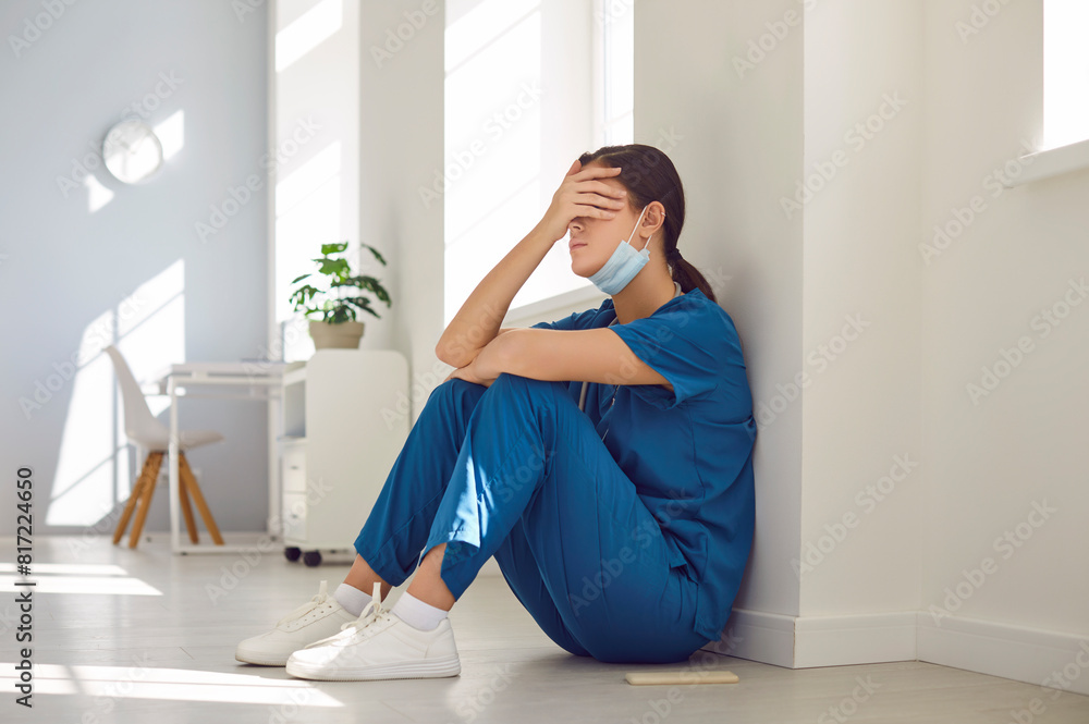 Exhausted stressed female nurse or doctor wearing blue face mask and ...