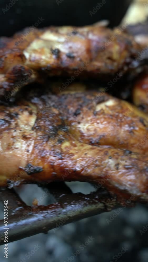 A rack of chicken is being cooked on a grill with Arepa. The chicken is ...