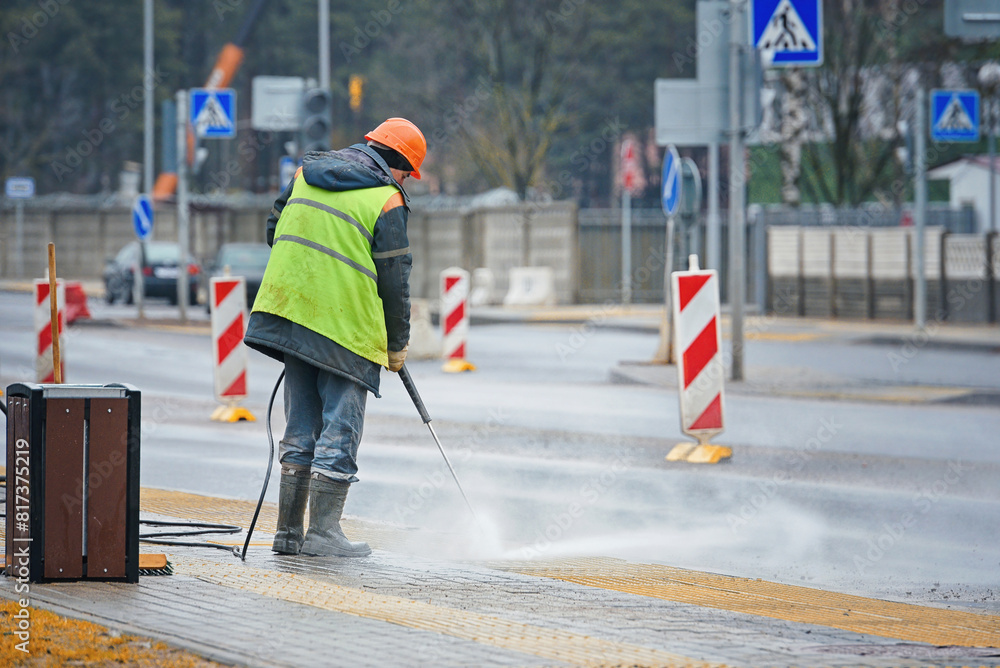 Construction worker cleaning city sidewalk with pressure washer after ...