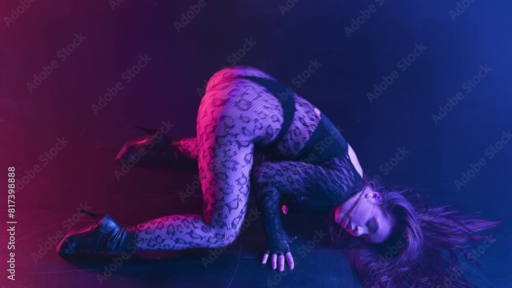 Alluring woman dancing flexible movements with body on floor. Erotic hot dance in dark studio ...