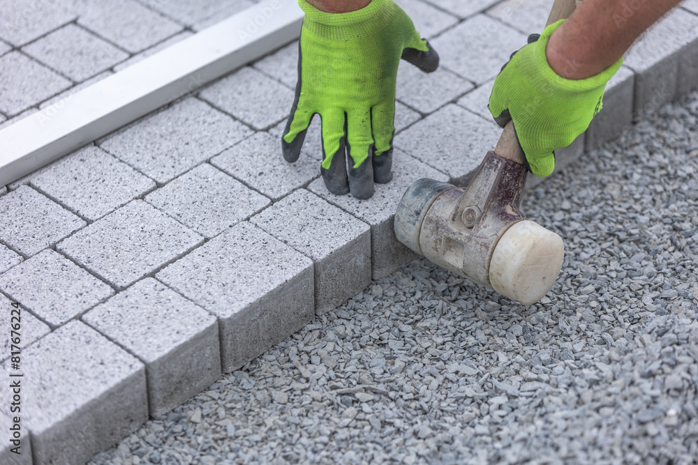 Worker building a sidewalk, laying interlocking pavers, walking path ...