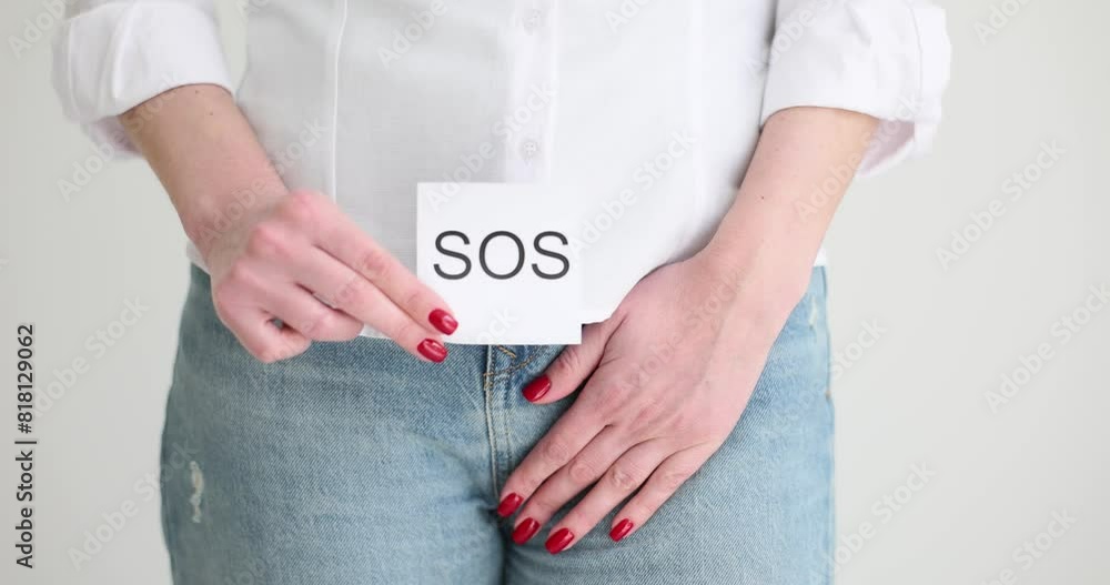 Female covers groin with hand and shows message SOS in light office ...