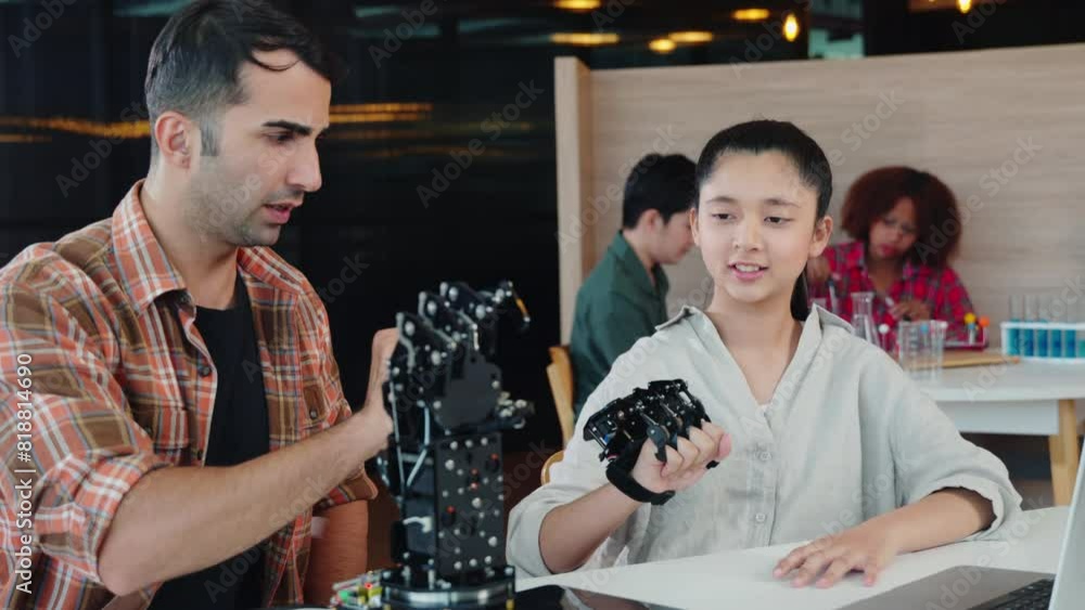 Teacher aids student constructing a robotic arm in classroom design and ...