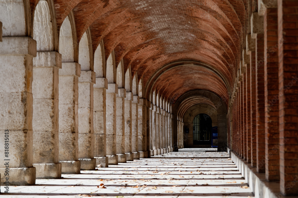 arched passageways are lined with white concrete pillars and brick ...