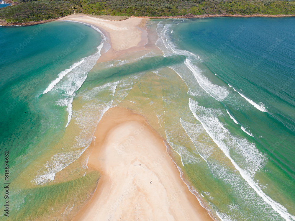 Aerial view of a sand spit with blue ocean on either side joined by ...