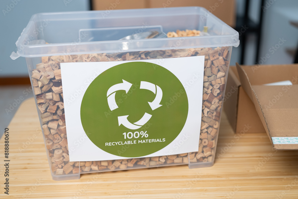 The focus is on a container labeled "100% Recyclable Materials" filled ...
