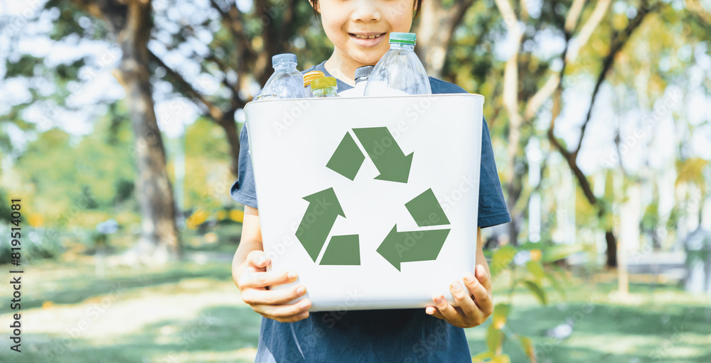 Cheerful young asian boy holding recycle symbol bin on daylight natural ...