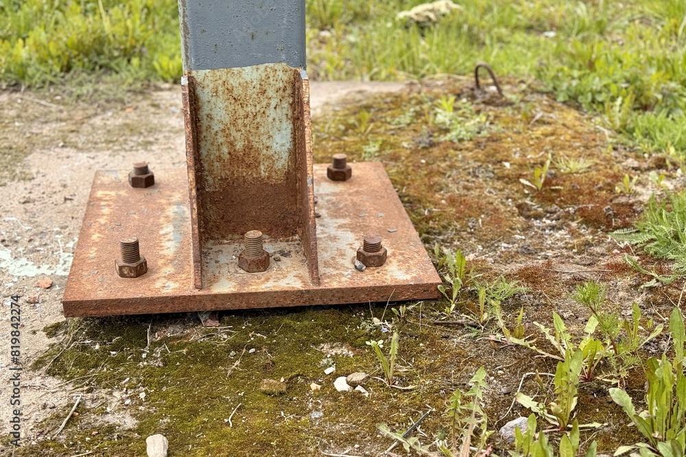 Metal pillar fastened to basement with anchor bolts and nuts. The rusty ...