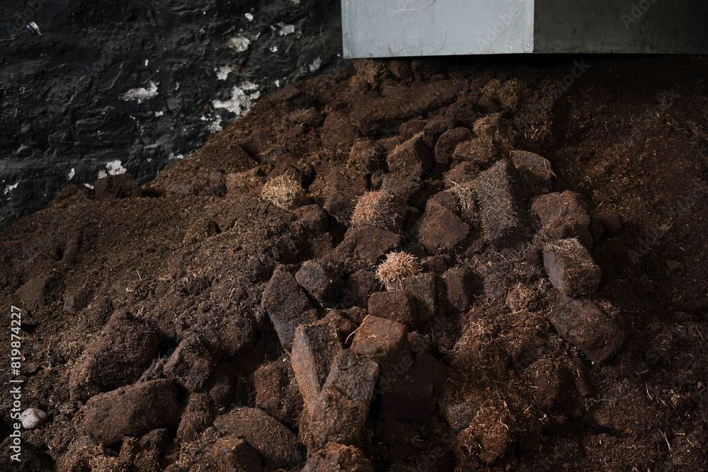 Dried lumps of peat in a whisky distillery. Peat is used to dry the ...