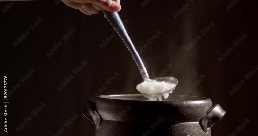 Slow motion while the cook is cooking rice porridge in a boiling clay ...