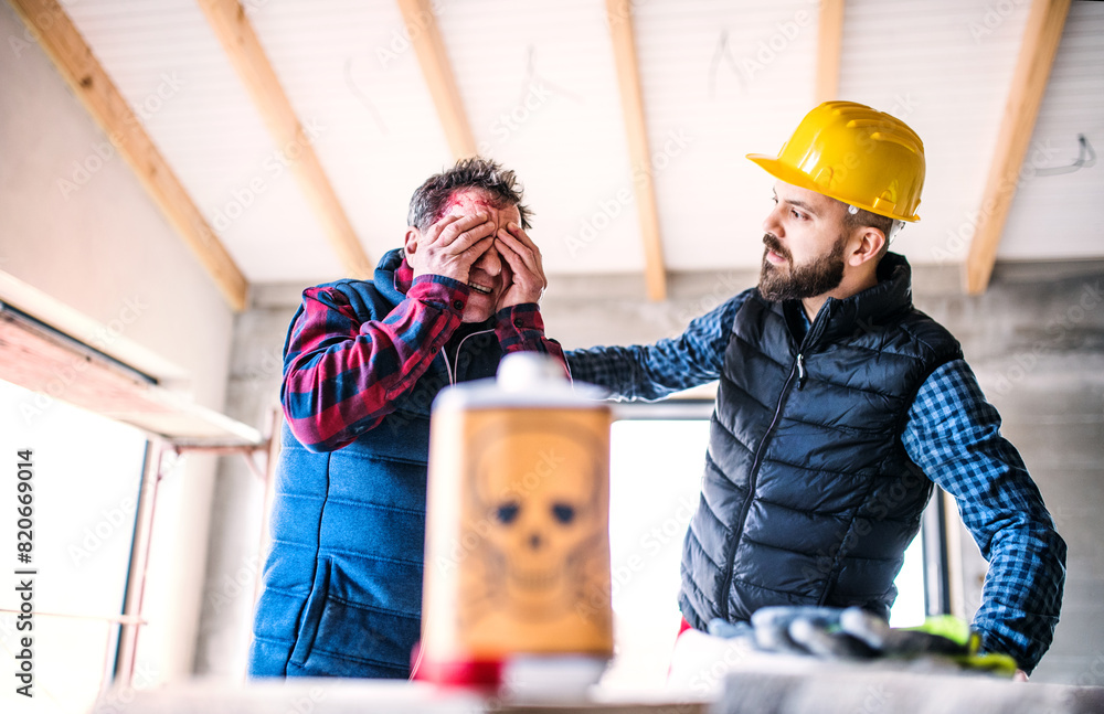 Colleague giving first aid to worker with chemical splashed on his skin ...