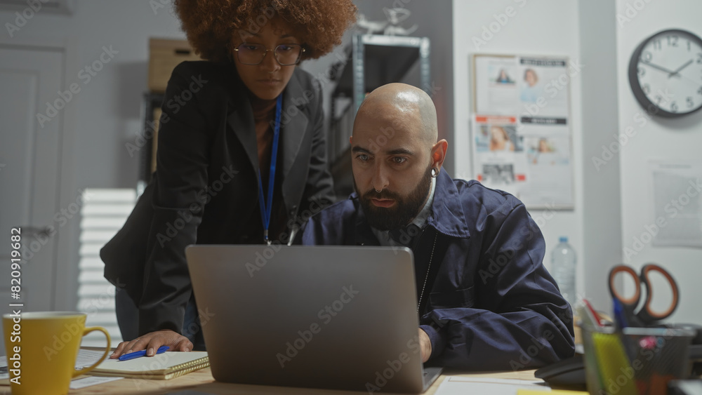 Man and woman in plainclothes working together at a cluttered desk ...