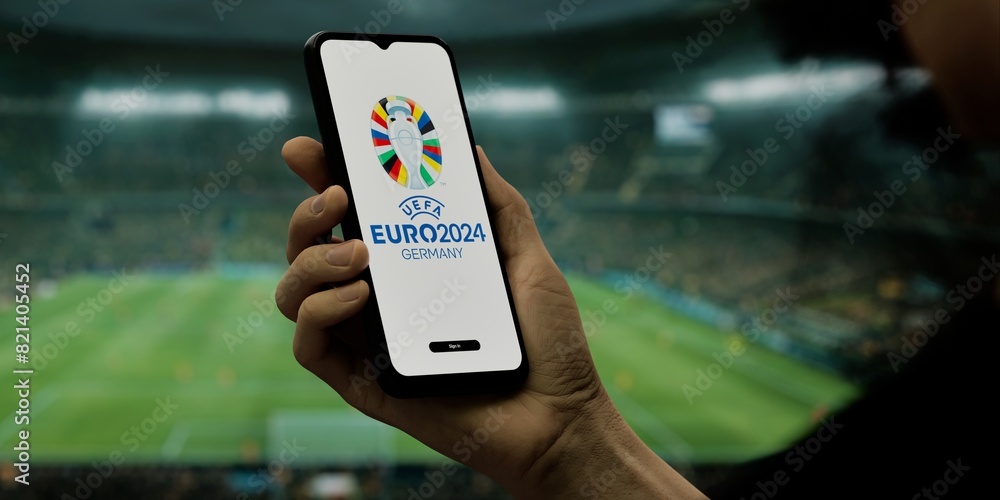 A hand holding a phone with the UEFA Euro 2024 app on a screen, against ...