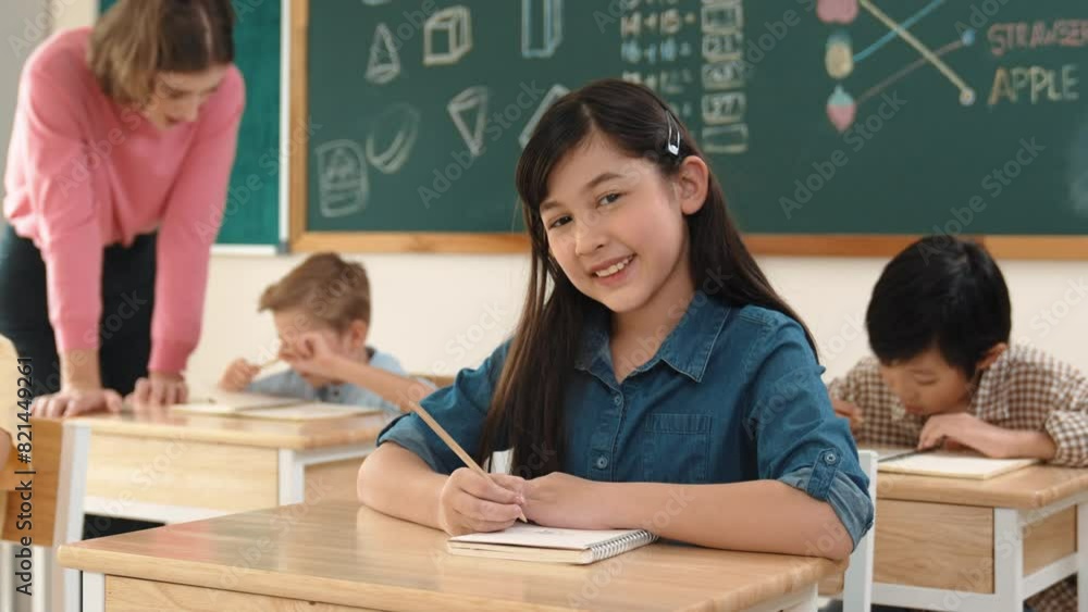 Asian girl writing test or classwork while looking at camera at ...