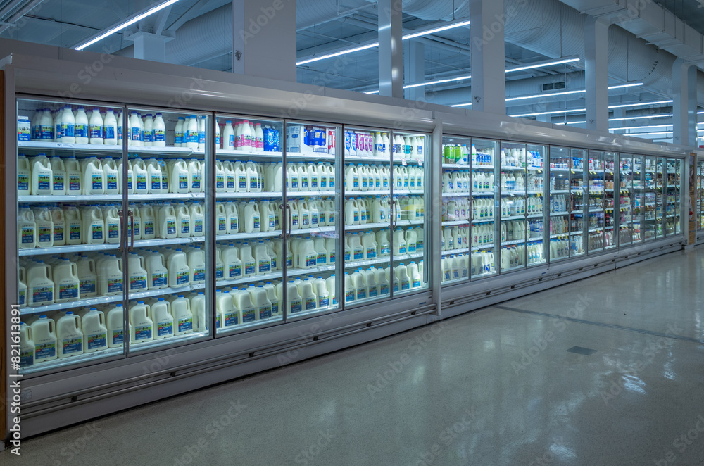 An aisle of fridge cabinets with many milk and dairy products of ...