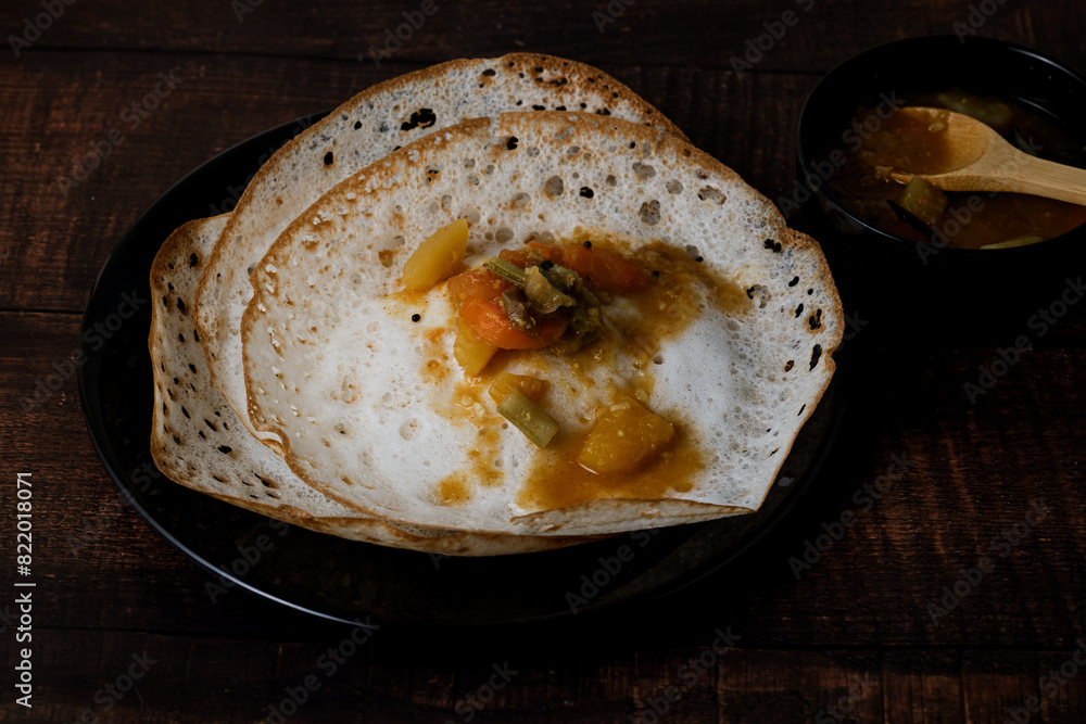 Aappam with Sambar on a wooden table. Appam or Palappam is one of the ...