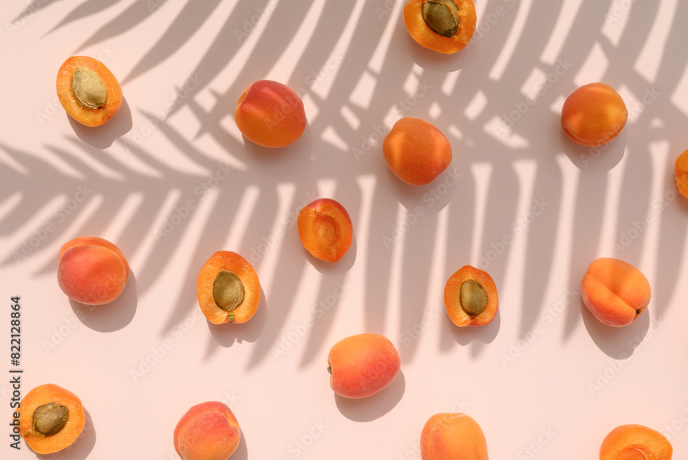 Apricot fruit with palm leaves shadow on a pastel pink background ...