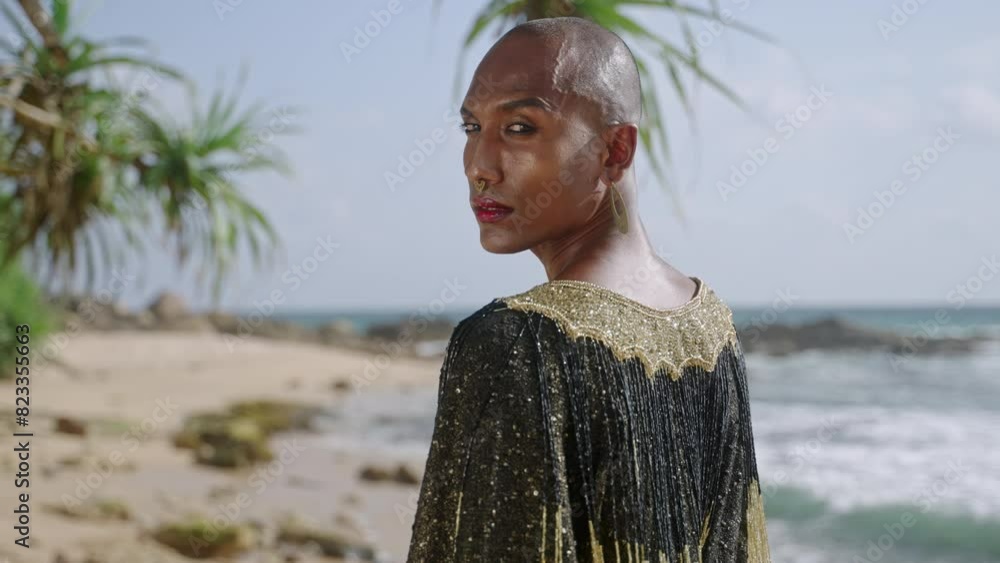 LGBTQIA black person in luxury dress walks, turns back on stunning sea ...