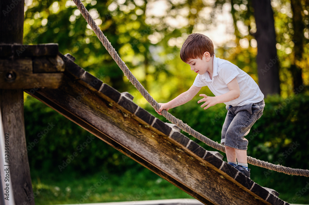A young boy in a white shirt and denim shorts enthusiastically climbs a ...