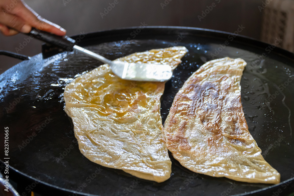 Cooking roti, a type of flatbread. The roti is being cooked on a large ...