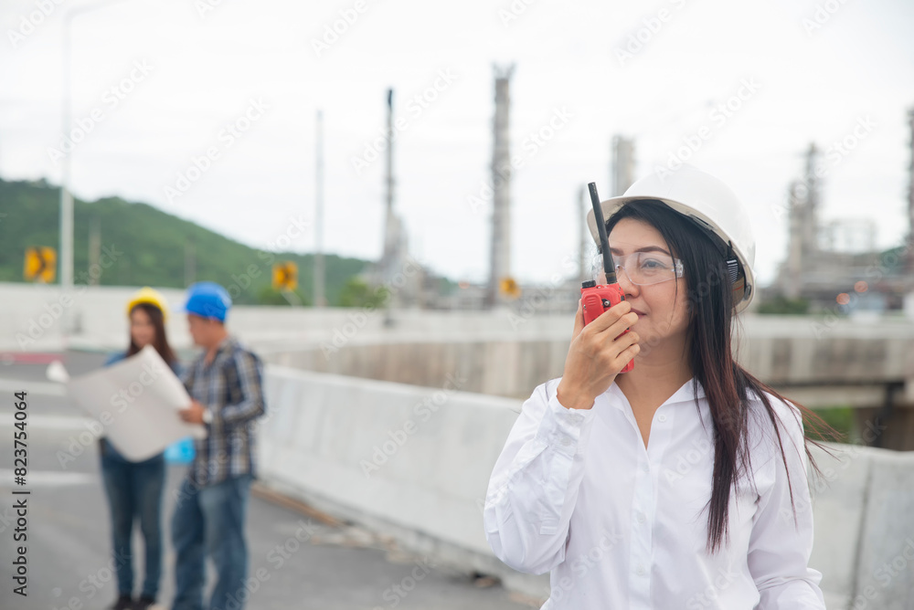 Civil Engineer holding portable radio, blueprint at refinery plant ...