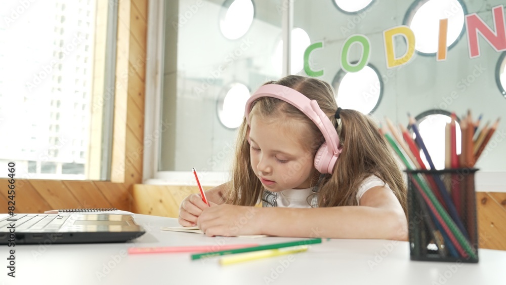 Cute smart girl doing classwork or online learning while listen to ...