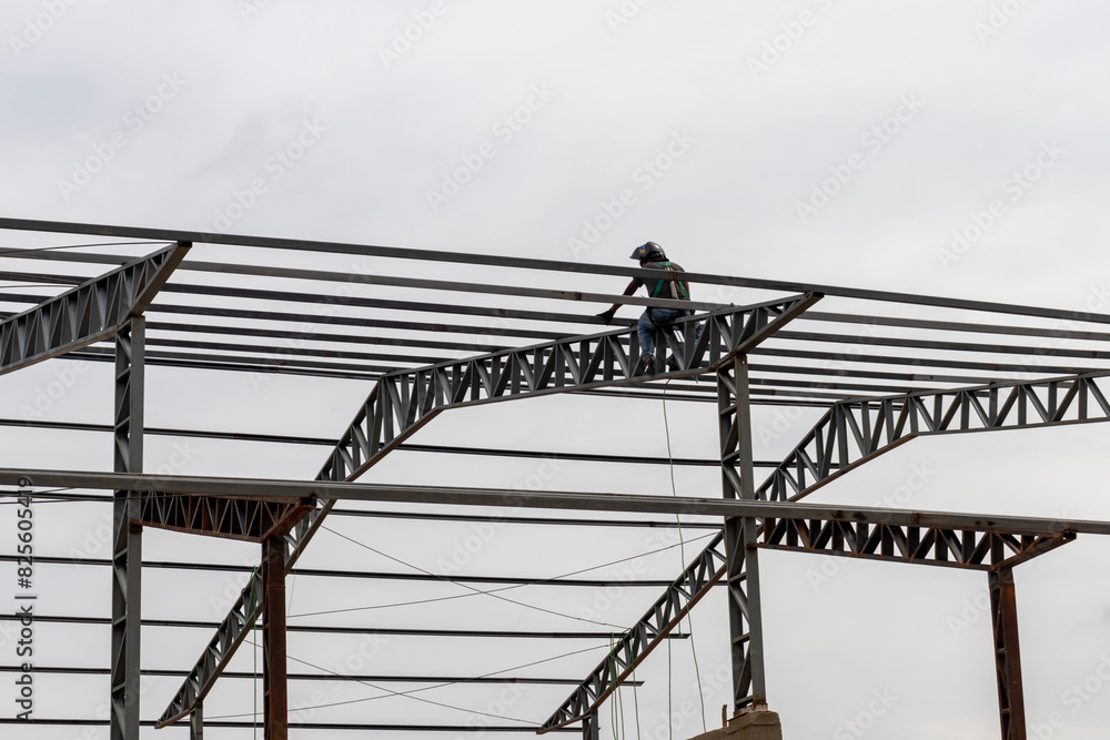 Man working at height assembling metal structure for warehouse ...