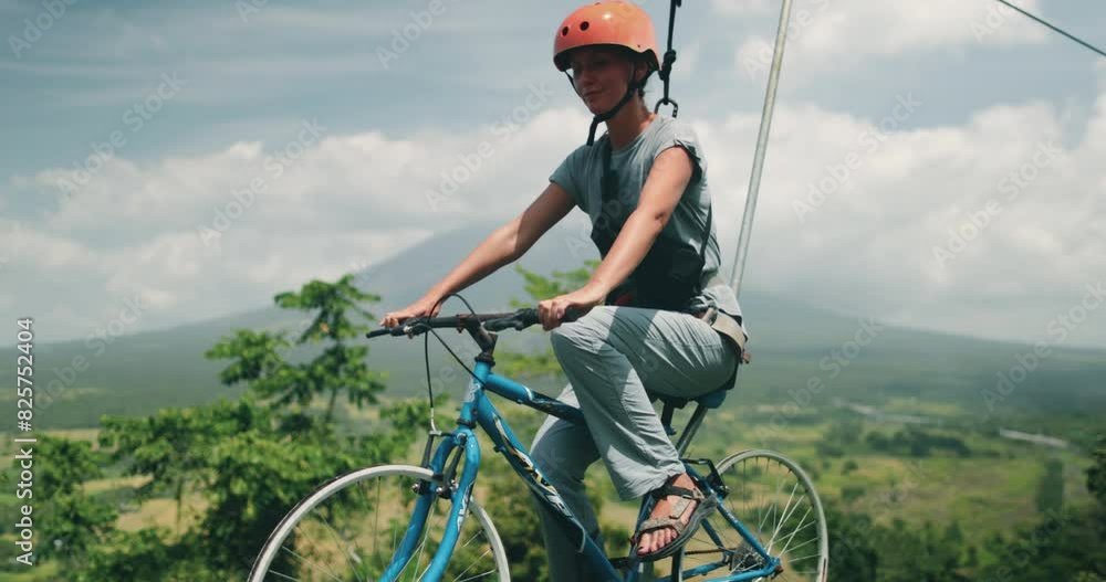 A womani riding a bike on top of a zip line over the beautiful volcanic ...