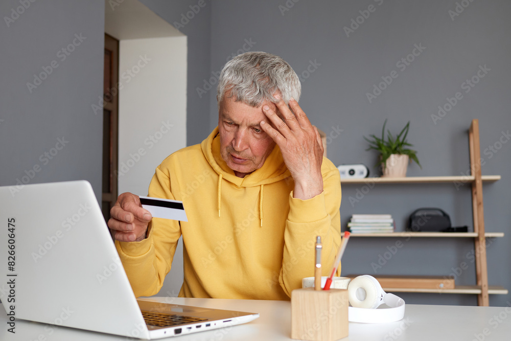 Sad unhappy upset senior man using laptop and holding credit card while ...